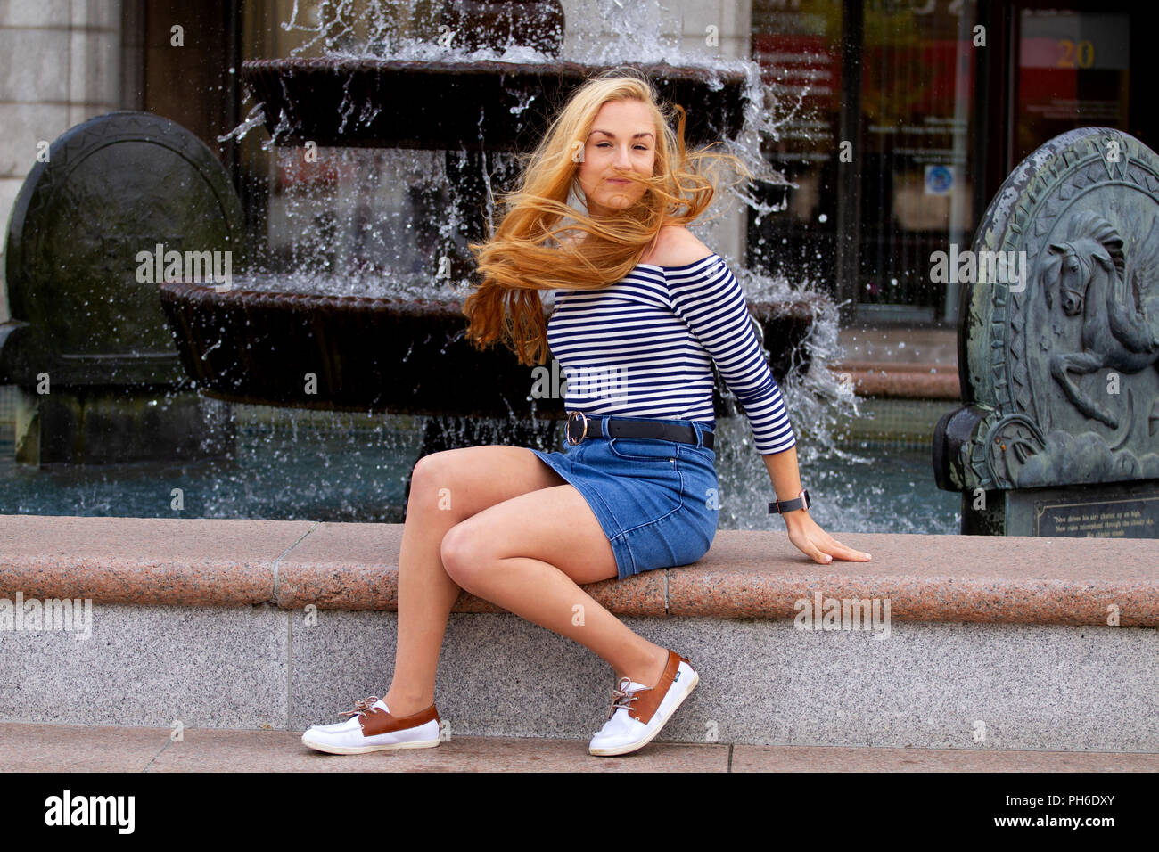 A young woman (Rhianna Martin) sitting beside the City Square fountain ...