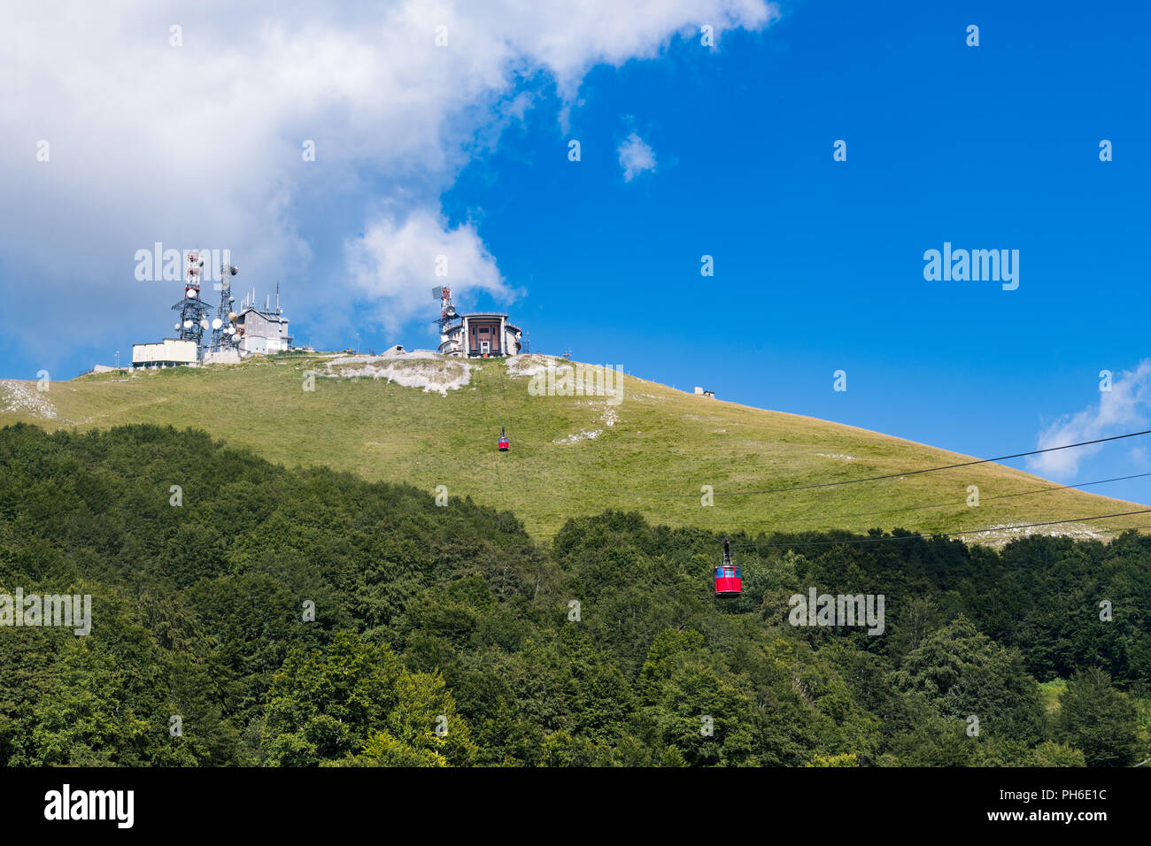 Landscape view of green mountain with red cable cars climbing path ...