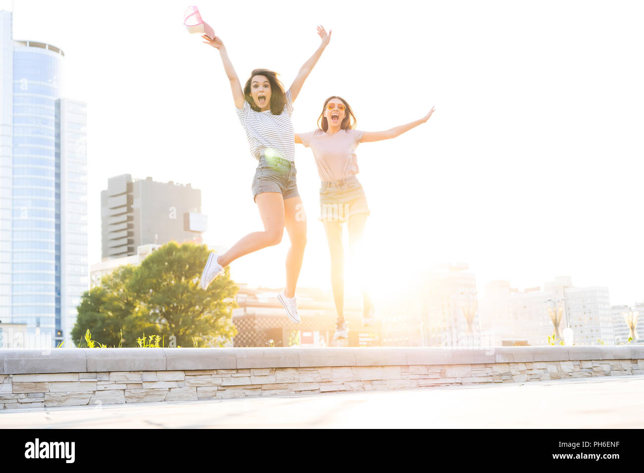 Two young happy hipster girls having fun, smiling, laughing, jumping ...