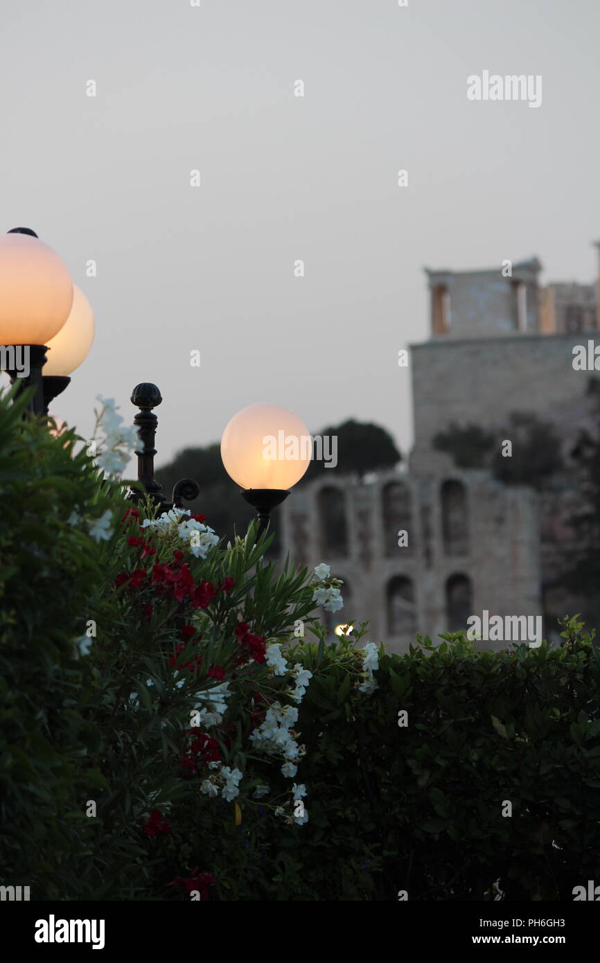 Lights and flowers at dusk backed by the arches below the Acropolis in ...
