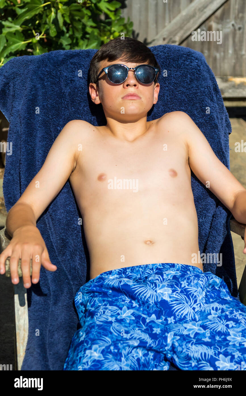 Caucasian teenage boy sunbathing in a garden wearing sunglasses Stock ...