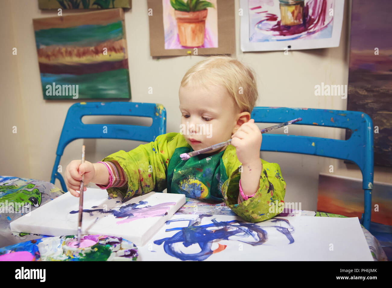 Cute adorable little baby boy girl toddler sitting in art studio ...