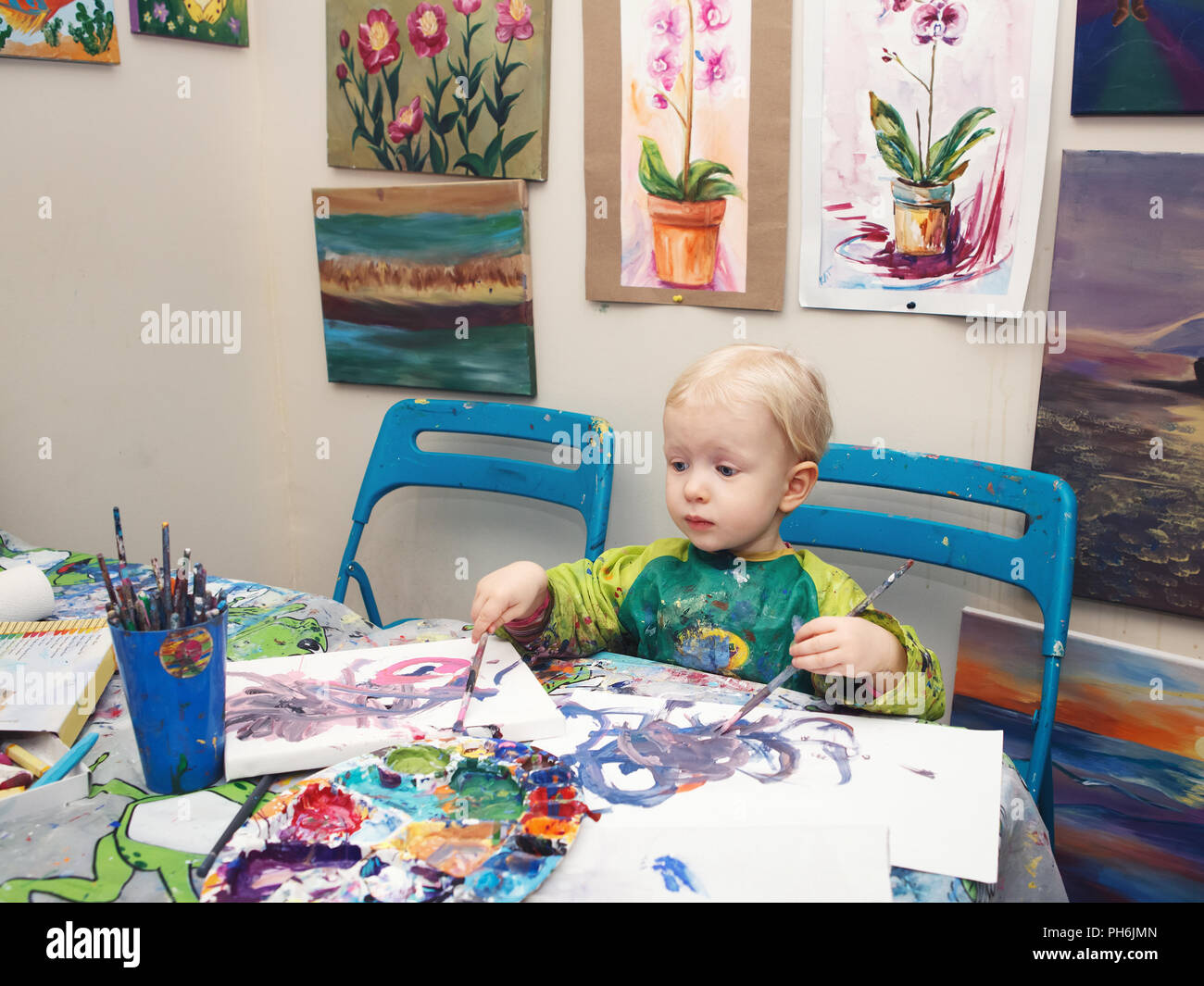 Cute adorable little baby boy girl toddler sitting in art studio ...
