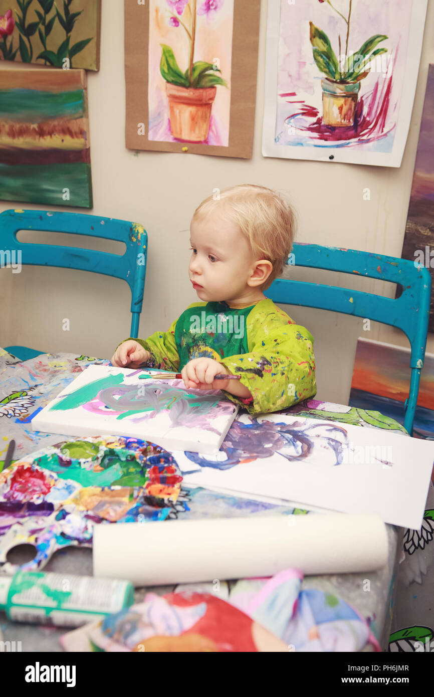 Cute adorable little baby boy girl toddler sitting in art studio ...