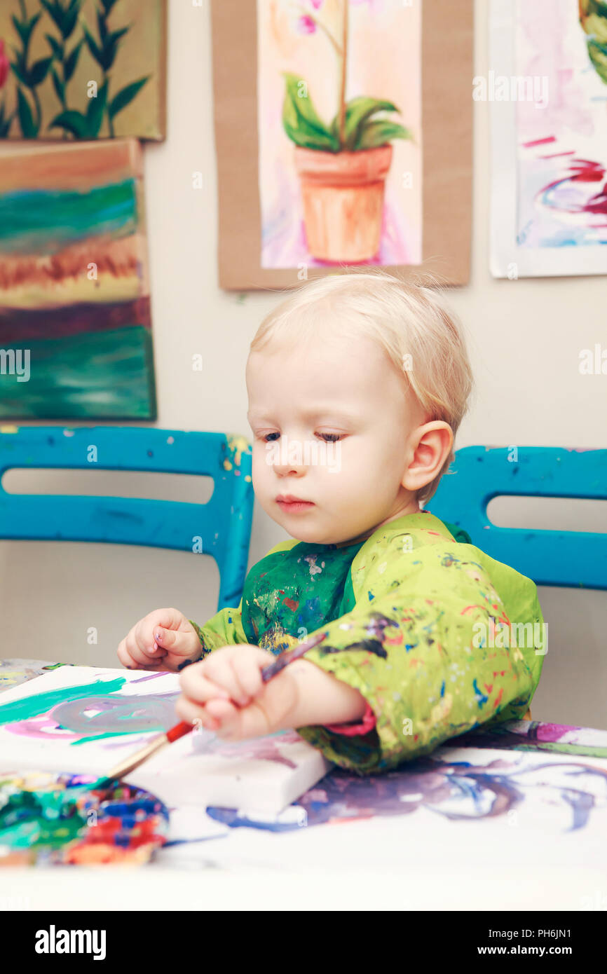 Cute adorable little baby boy girl toddler sitting in art studio ...