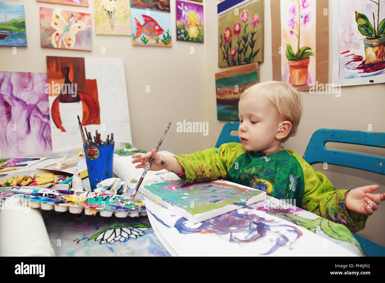 Cute adorable little baby boy girl toddler sitting in art studio ...