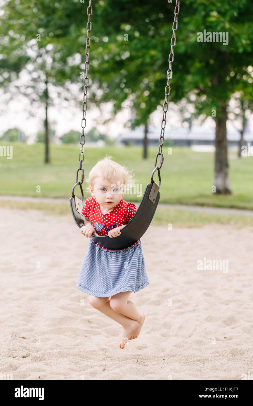 portrait-of-happy-smiling-little-toddler-girl-swinging-on-swings-at