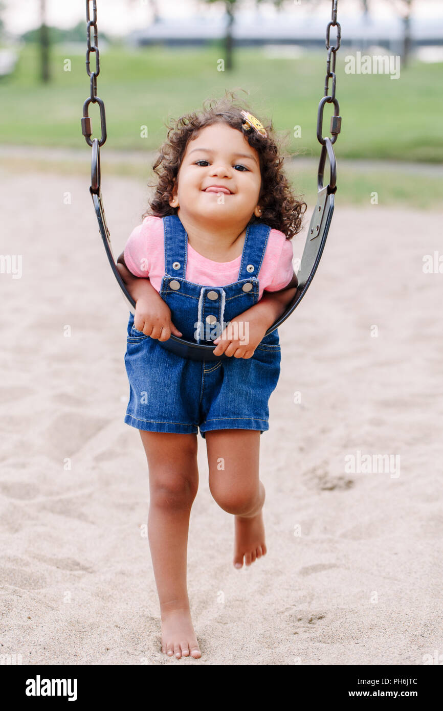 Portrait of happy smiling little latin hispanic toddler girl swinging ...