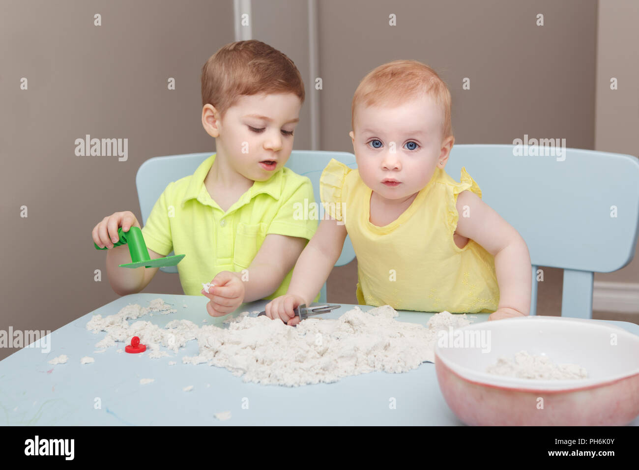 Group portrait of two cute siblings children playing kinetic sand or ...