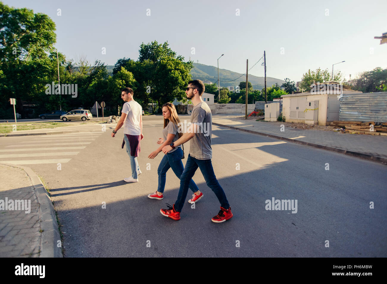 Happy group of young people walking across the street Stock Photo - Alamy
