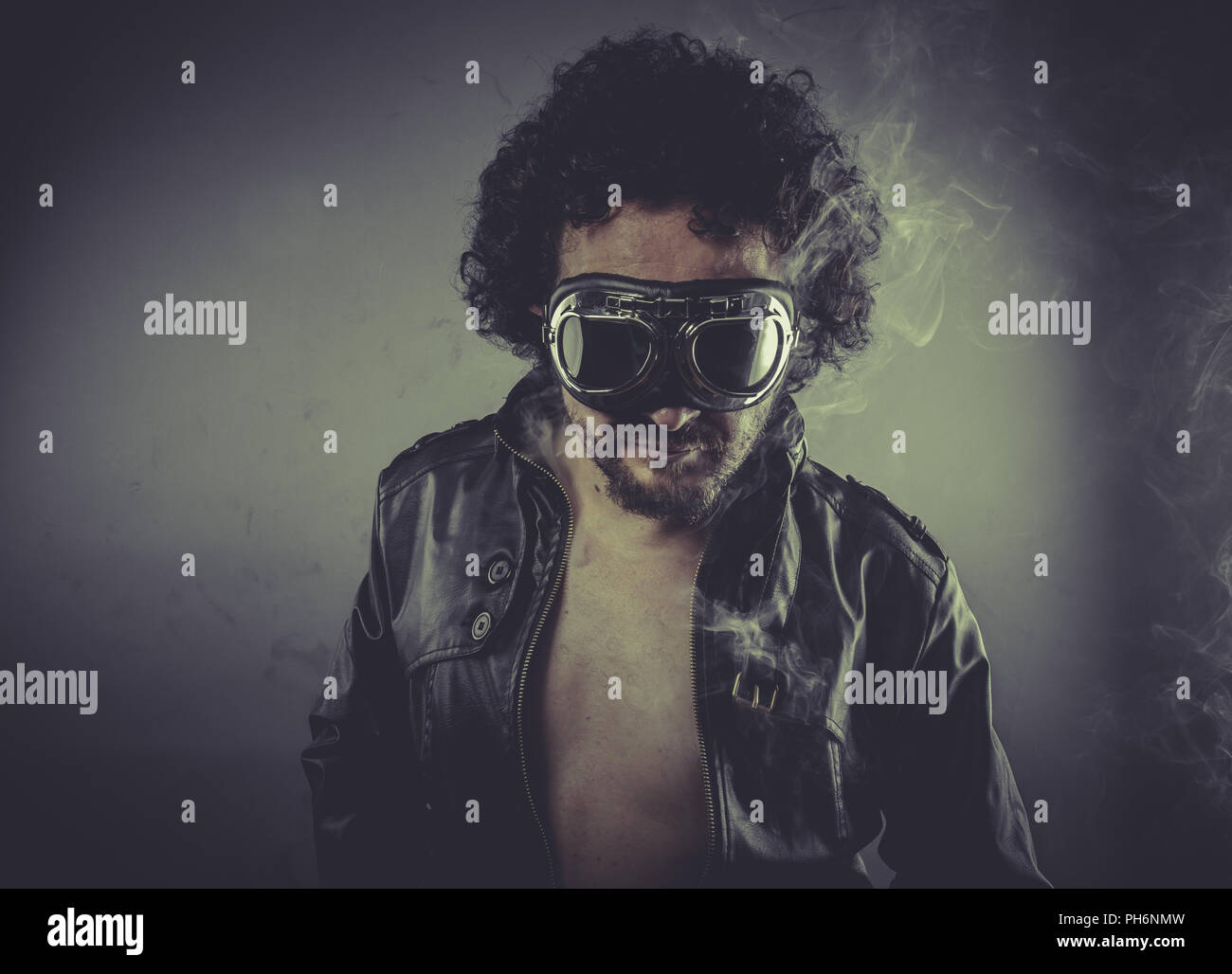 Biker speed, man with googles and black coat, smoke and dark background ...