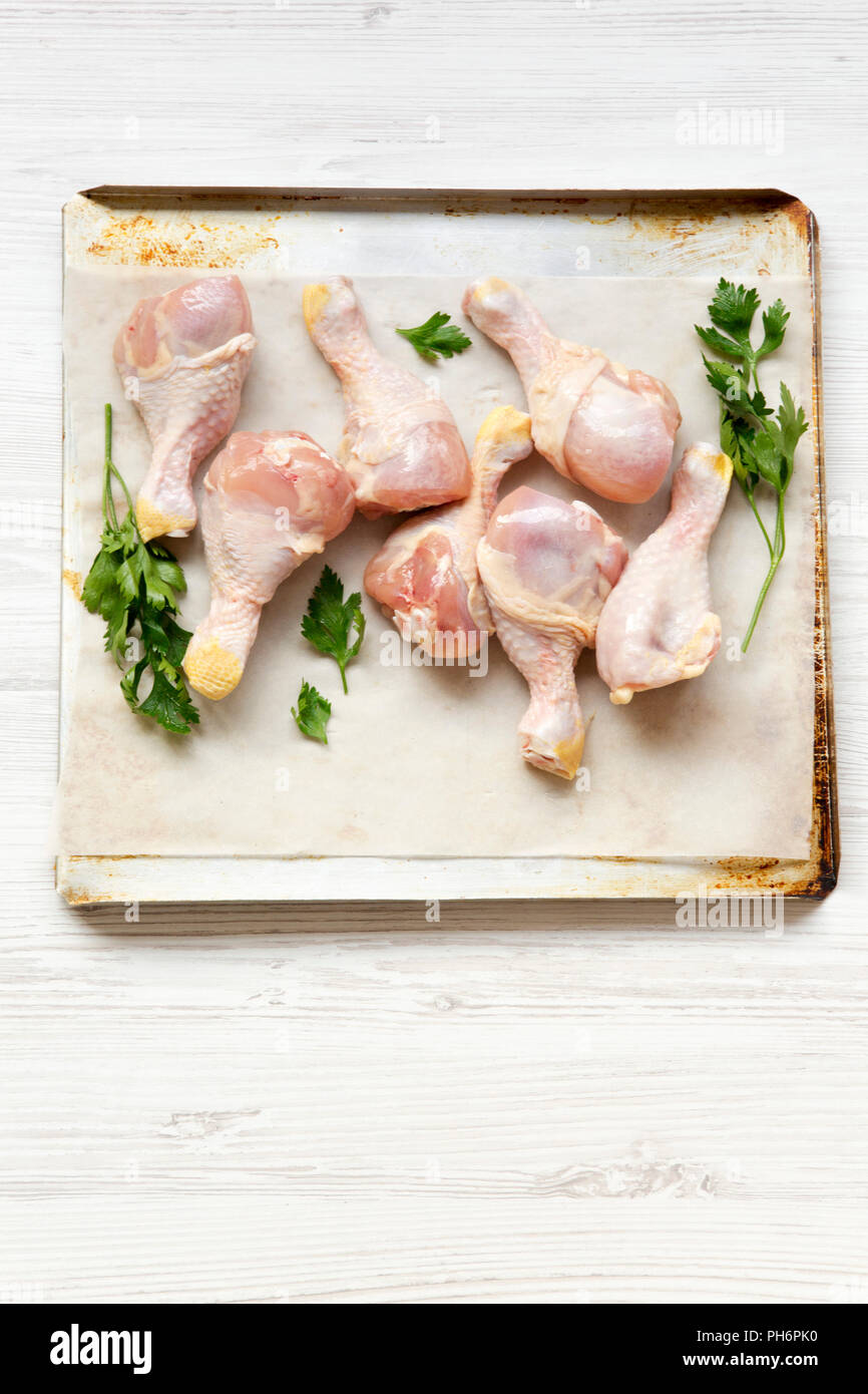 Uncooked chicken legs on a baking sheet paper on tray, high angle view ...