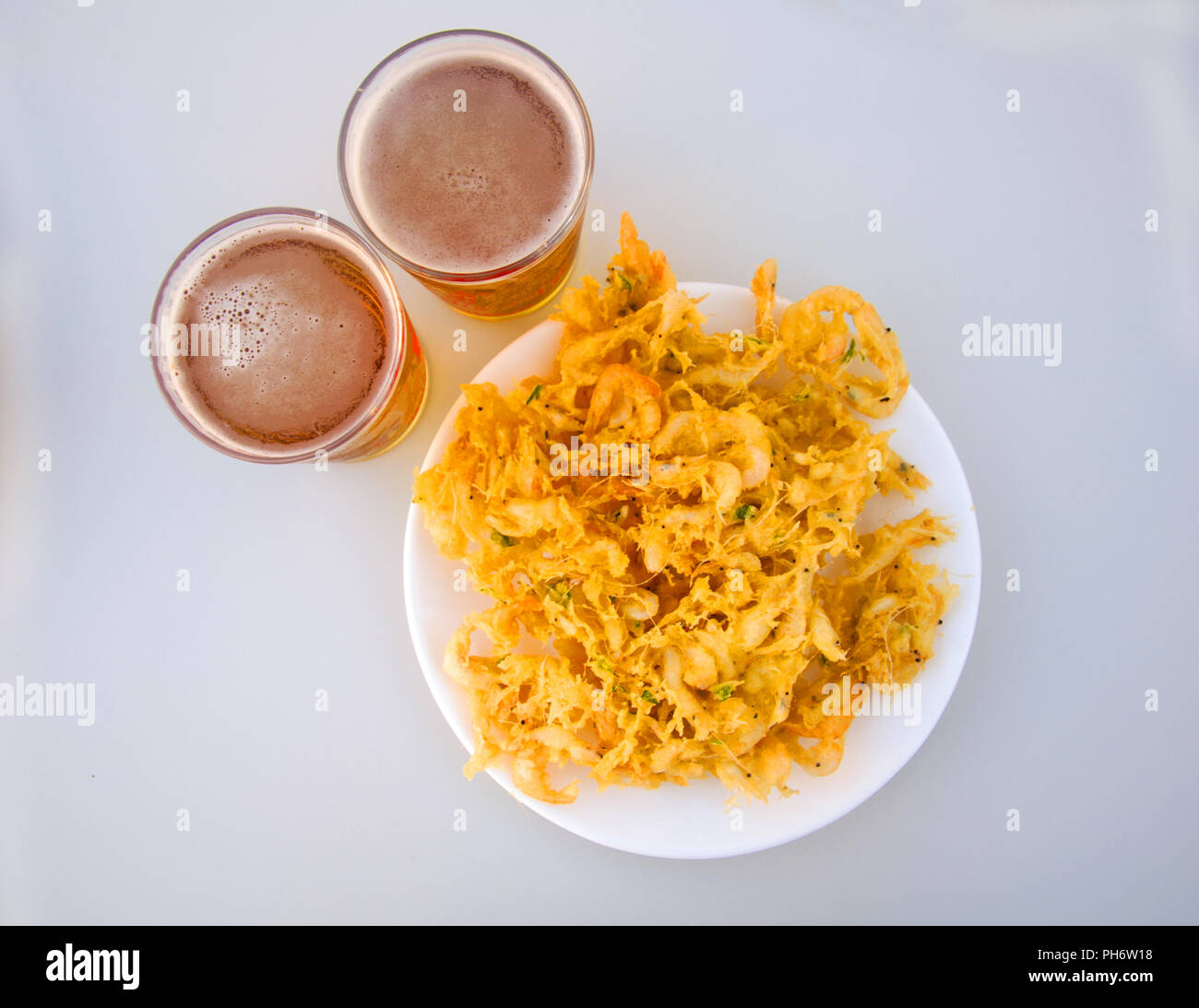 Fried yellow fritters with small shrimps and two beers, isolated Stock ...