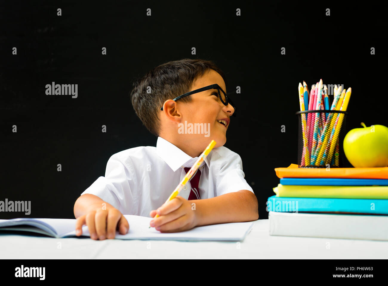 Cute smart handsome school boy in white shirt with eye glasses, writing ...