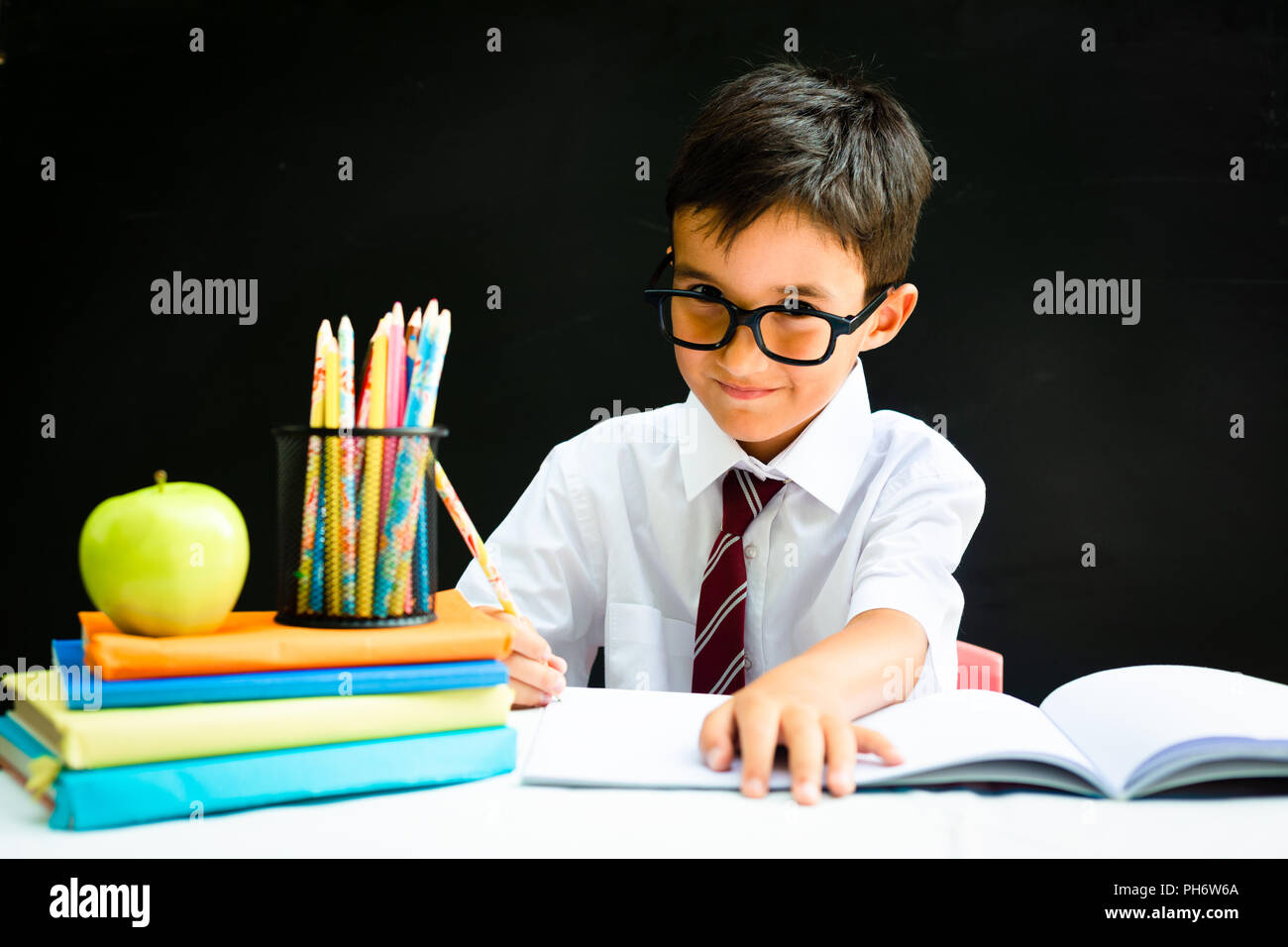 Cute smart handsome school boy in white shirt with eye glasses, writing ...