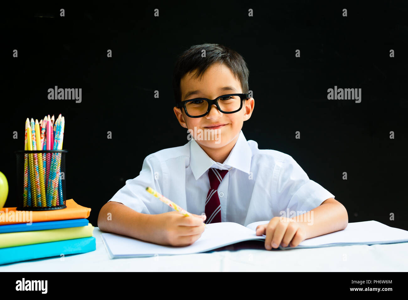 Cute smart handsome school boy in white shirt with eye glasses, writing ...