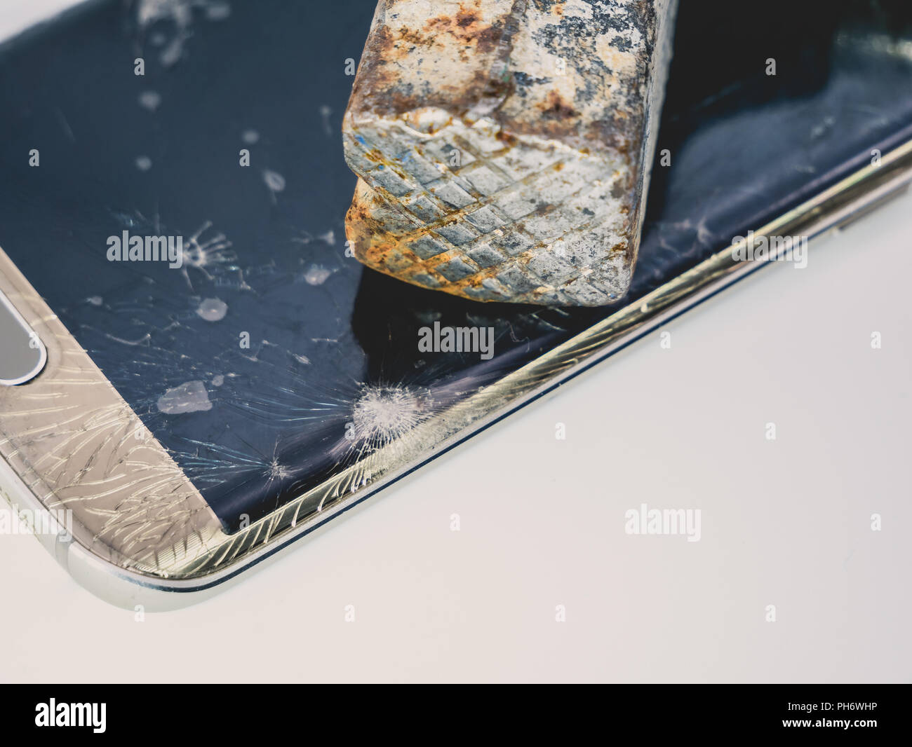 close-up of damaged smartphone display with hammer and white background ...