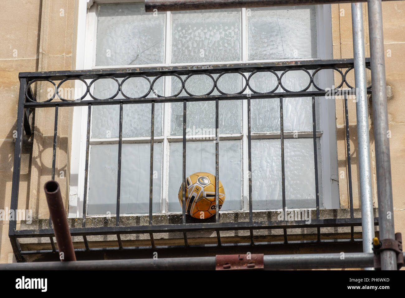 An orange football caught in an iron window balcony surround for a ...