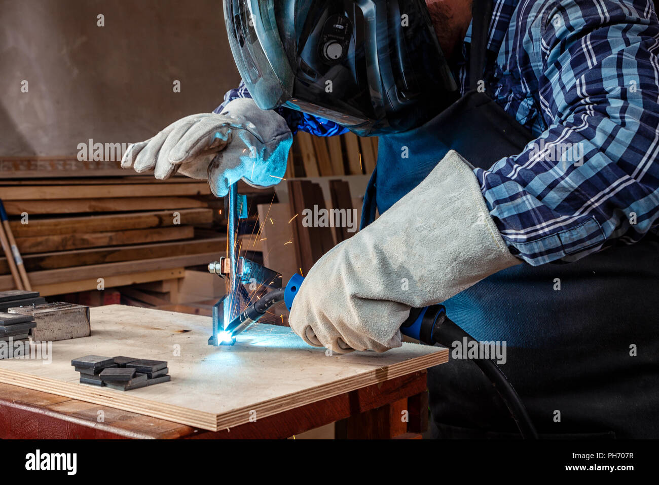 Strong man welder in work clothes hard working and welds with a welding ...