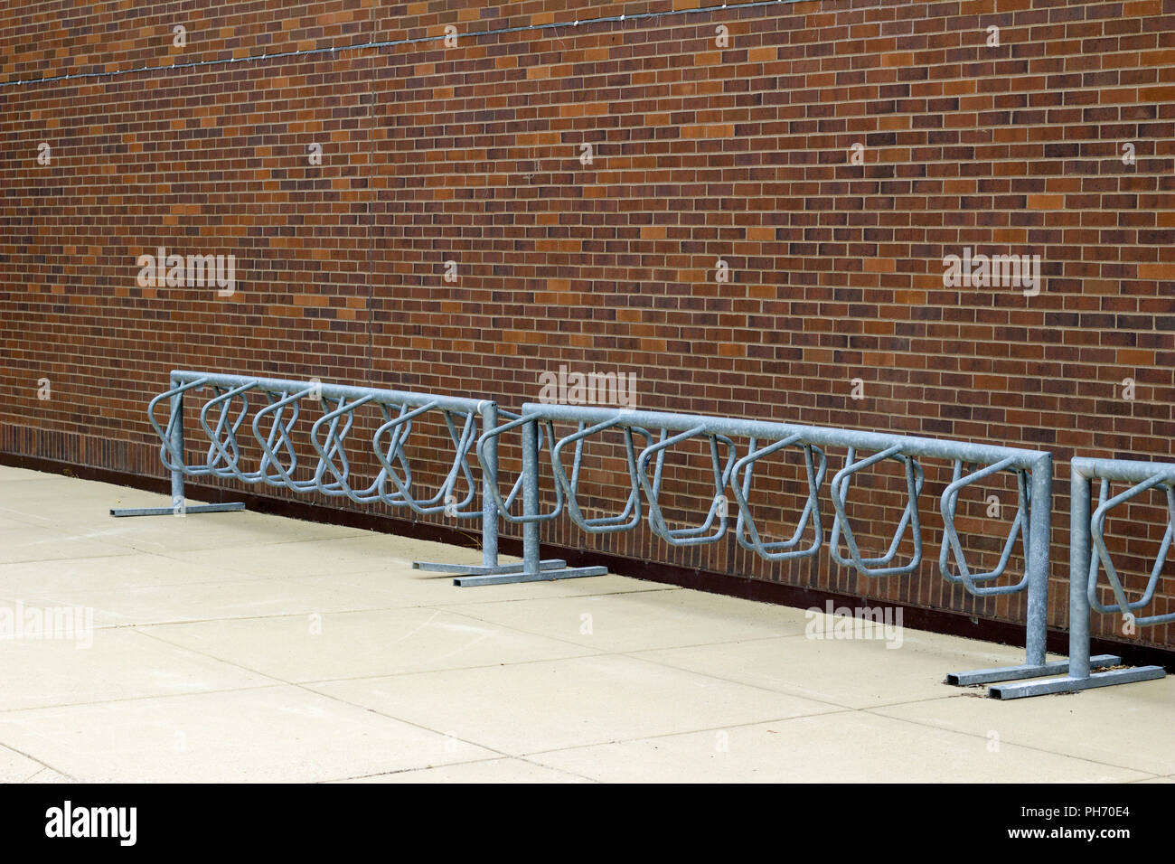 Sturdy metal bicycle rack in front of a vintage brown color brick wall ...