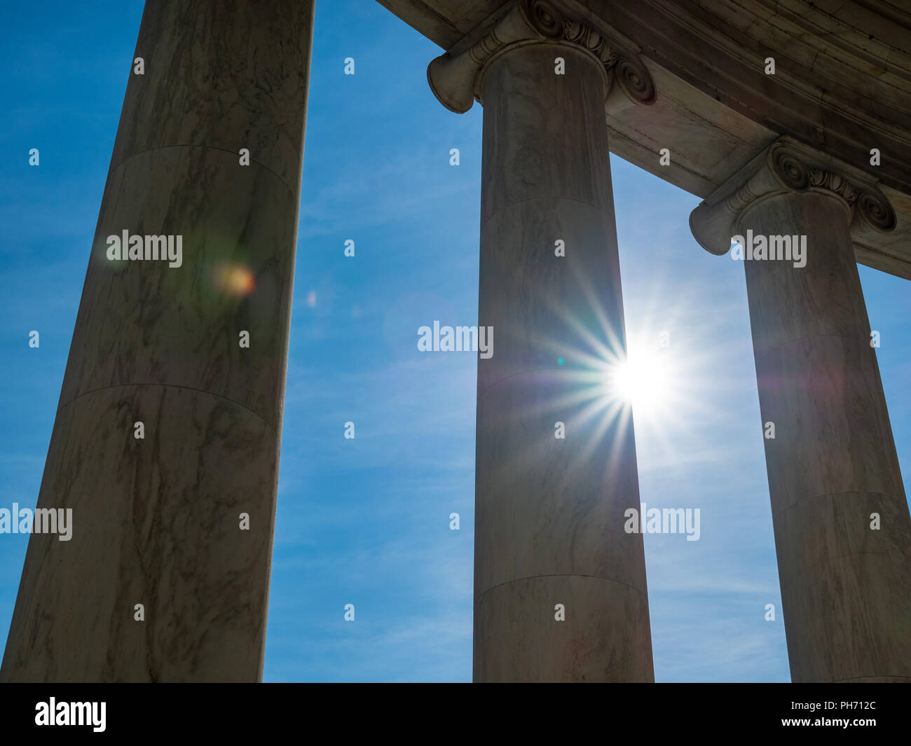 Sun, with some lens flair, shining through marble building columns ...