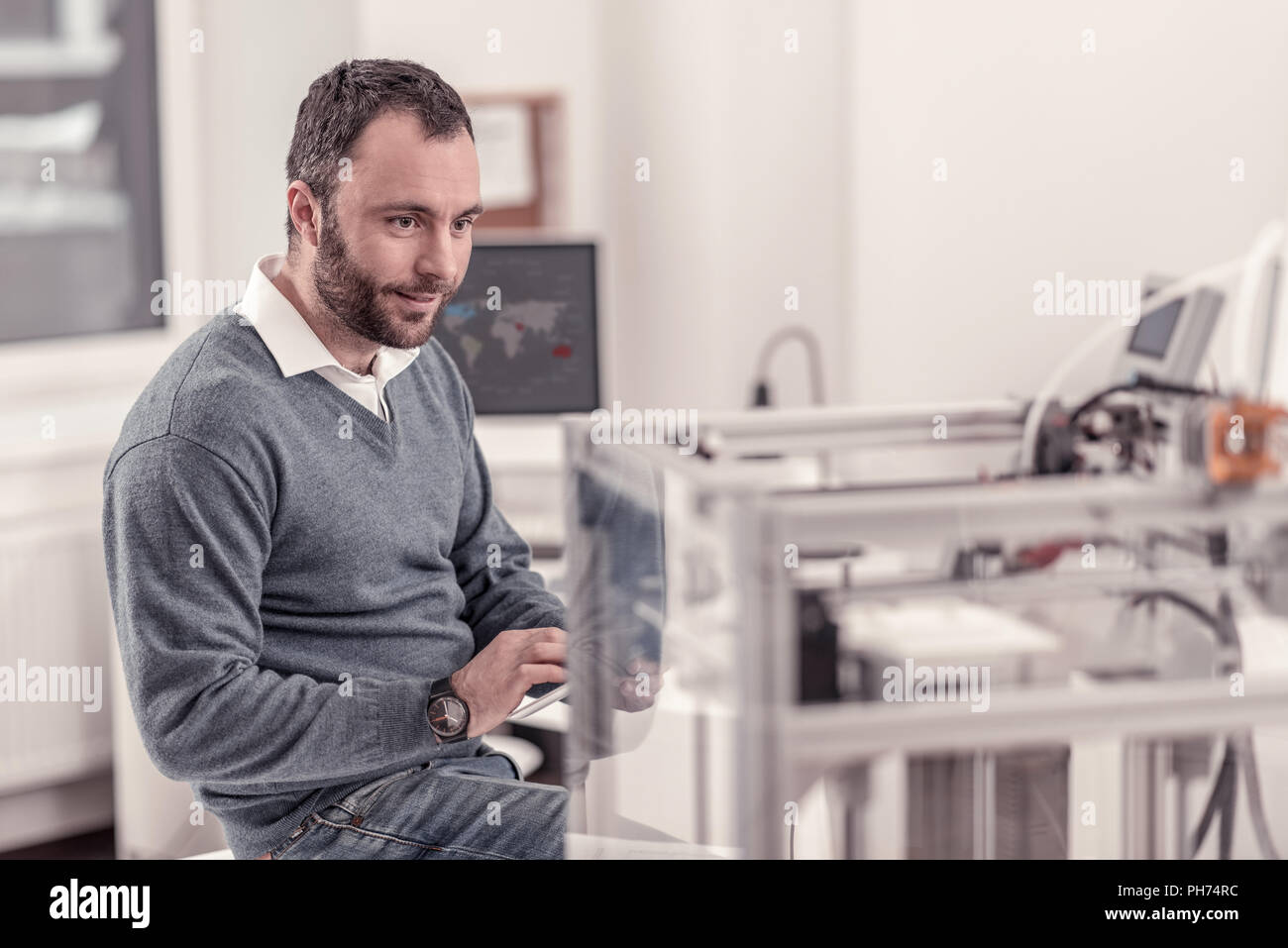 Pleasant adult man watching at 3D printer Stock Photo - Alamy