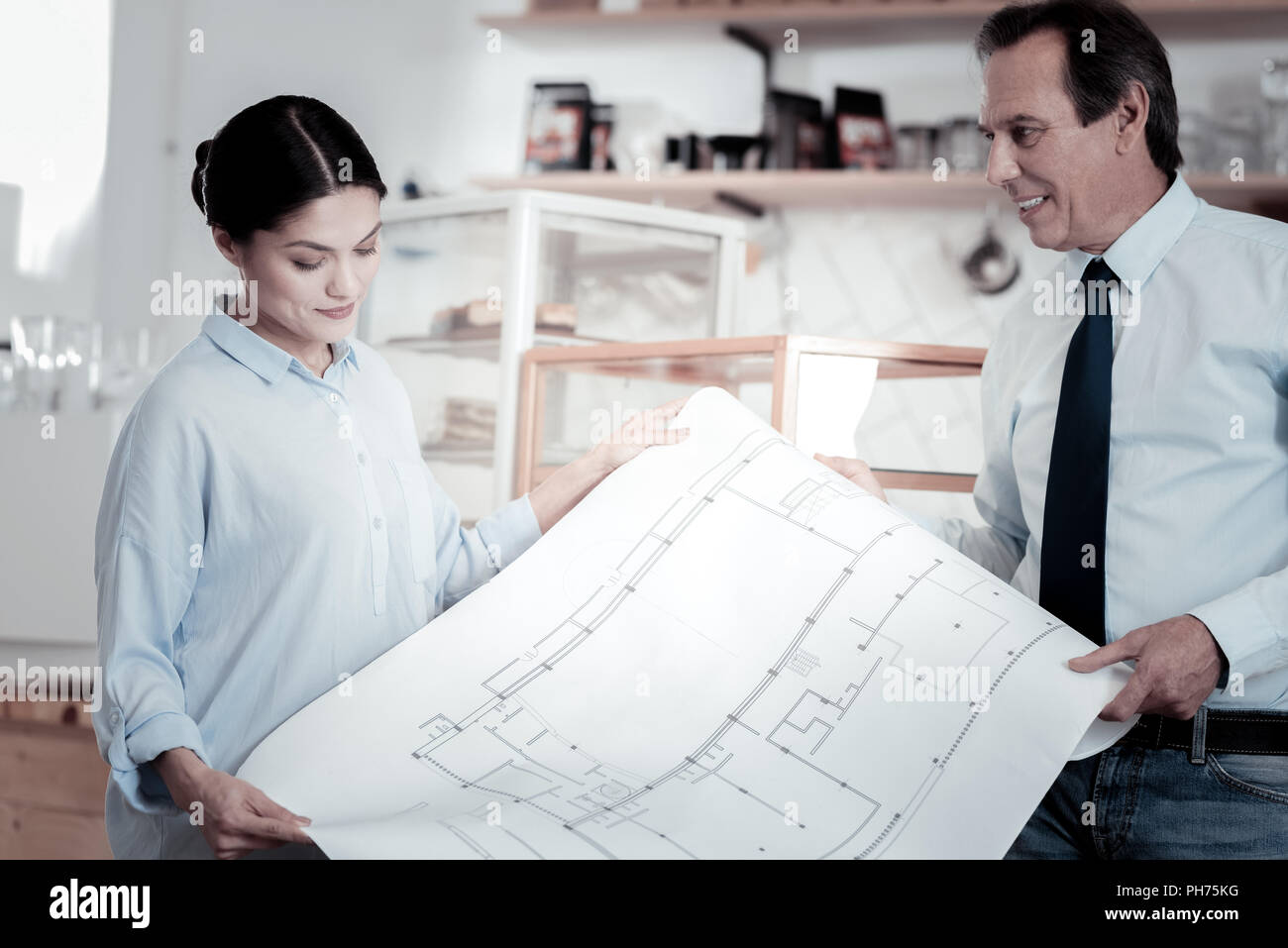 Curious engineers smiling and looking at the blueprint Stock Photo - Alamy