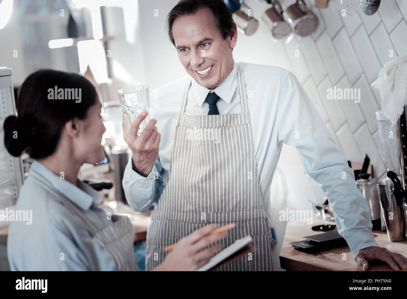 Positive waiter holding a glass and discussing it with a waitress Stock ...