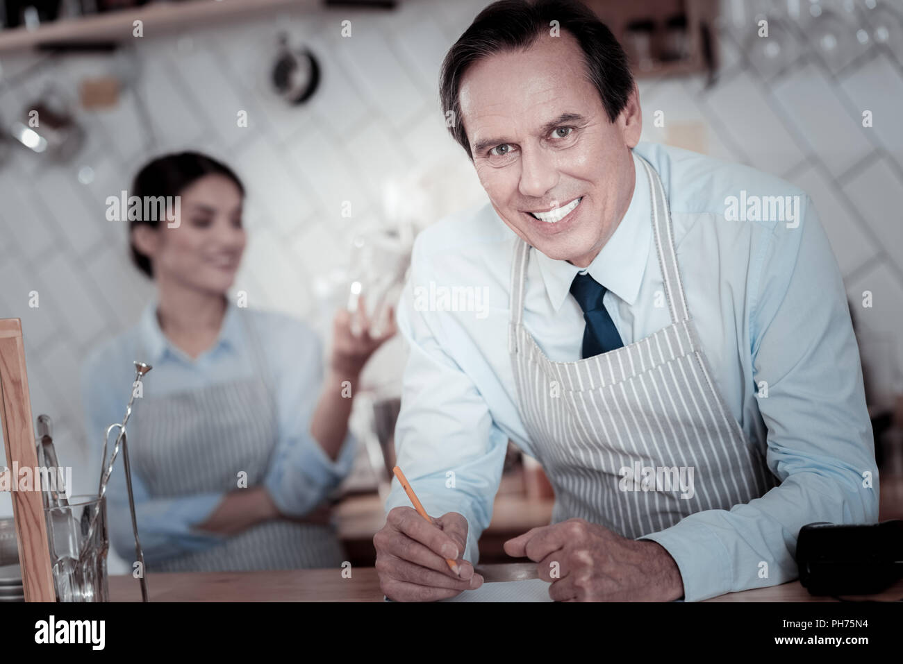 Smiling waiter making notes and feeling glad Stock Photo - Alamy