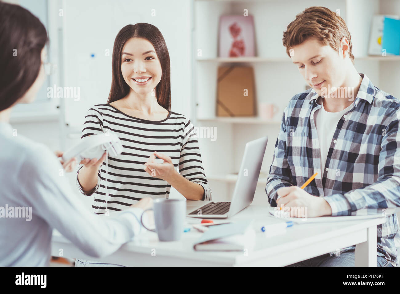 Nice young people sitting around the table Stock Photo - Alamy