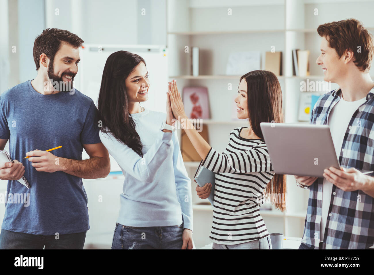 Positive young women giving high five to each other Stock Photo - Alamy