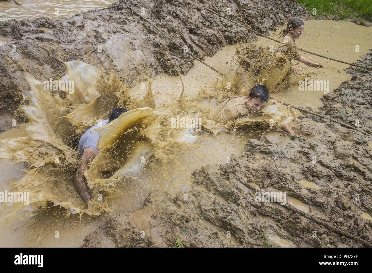 Participants jump into a mud pit during the annual Marine Corps ...
