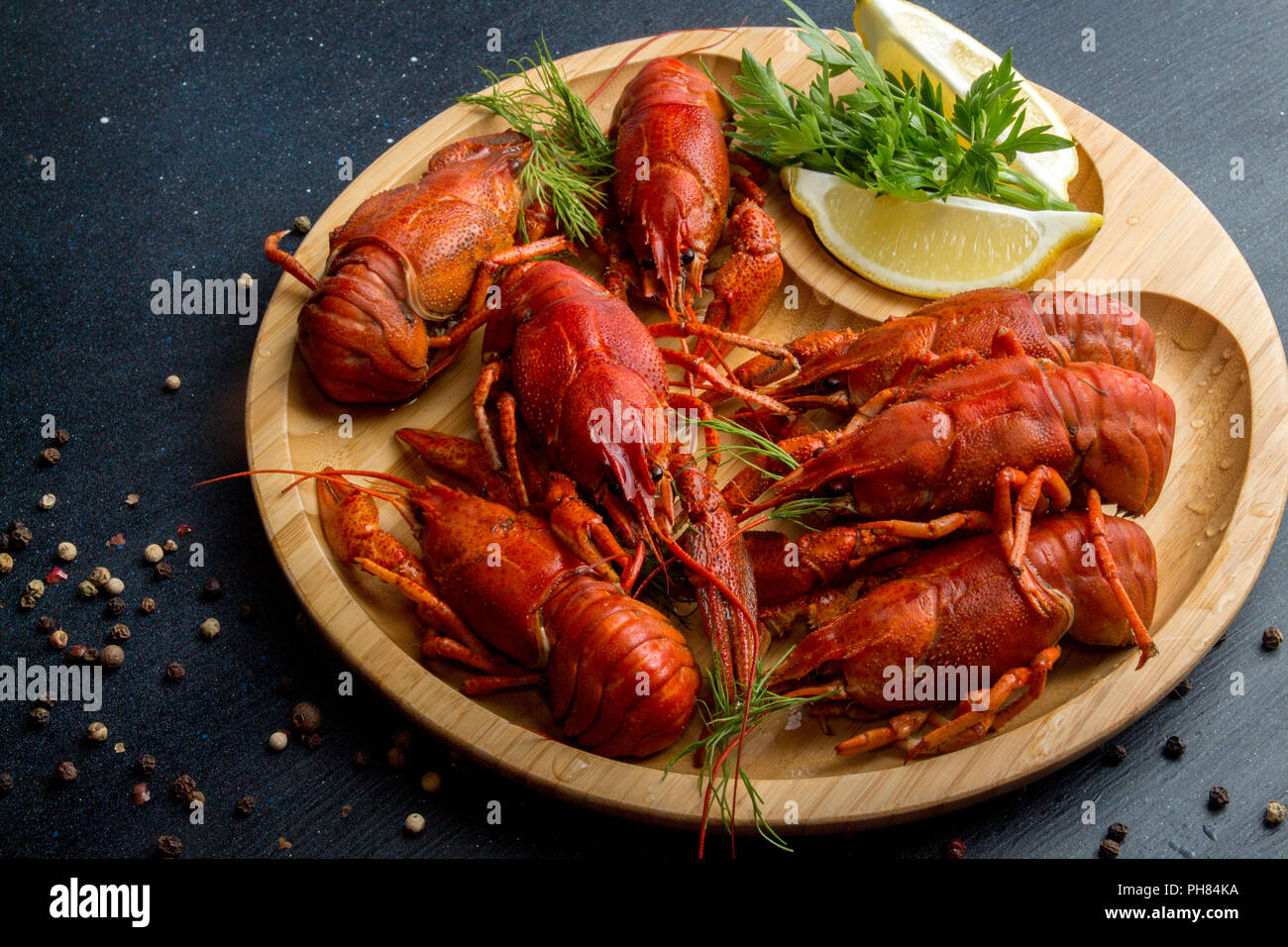 Boiled cooked crayfish crawfish ready to eat on wooden plate on black ...