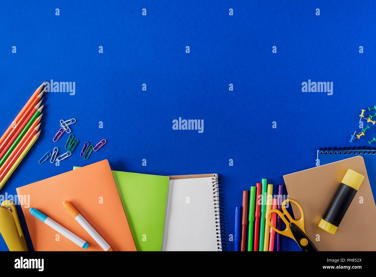 top view of empty textbook and variety stationery on blue background ...