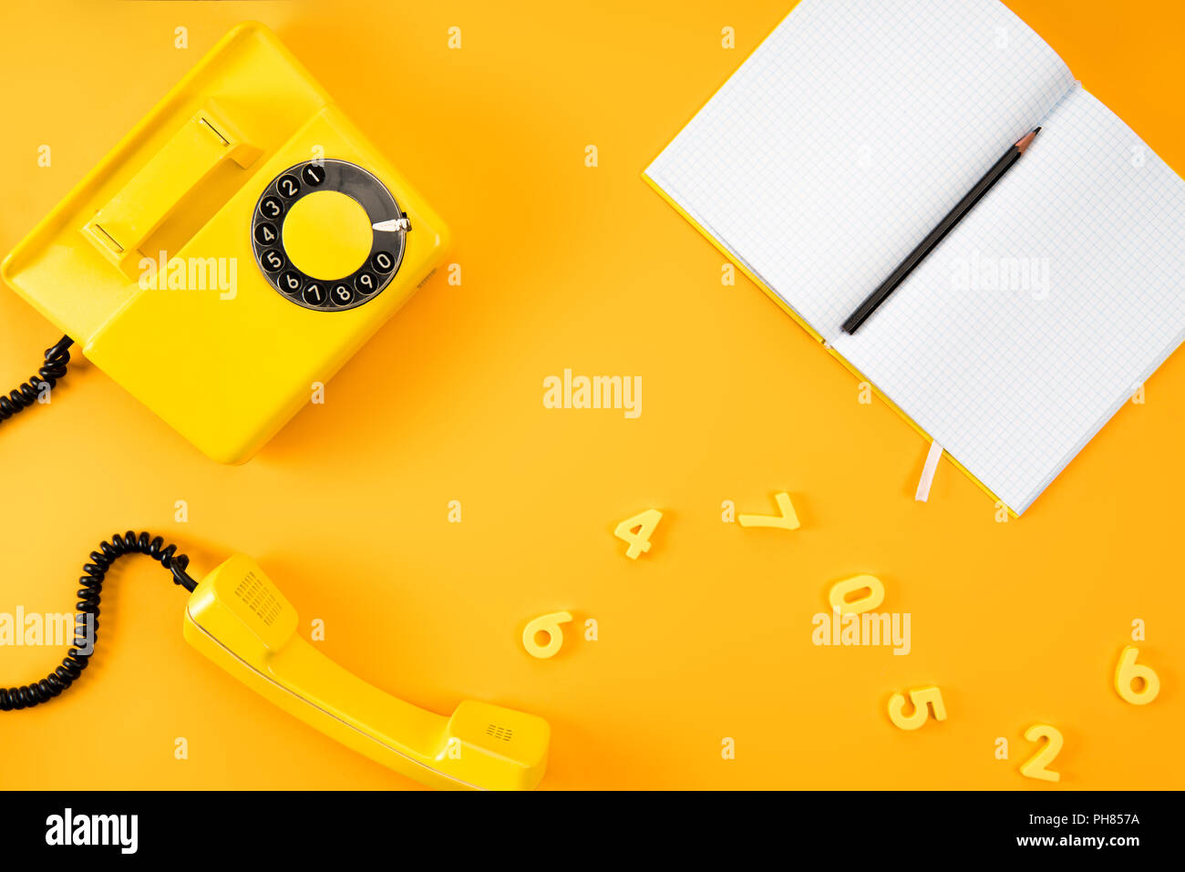 top view of vintage phone with blank notebook and numbers on yellow ...