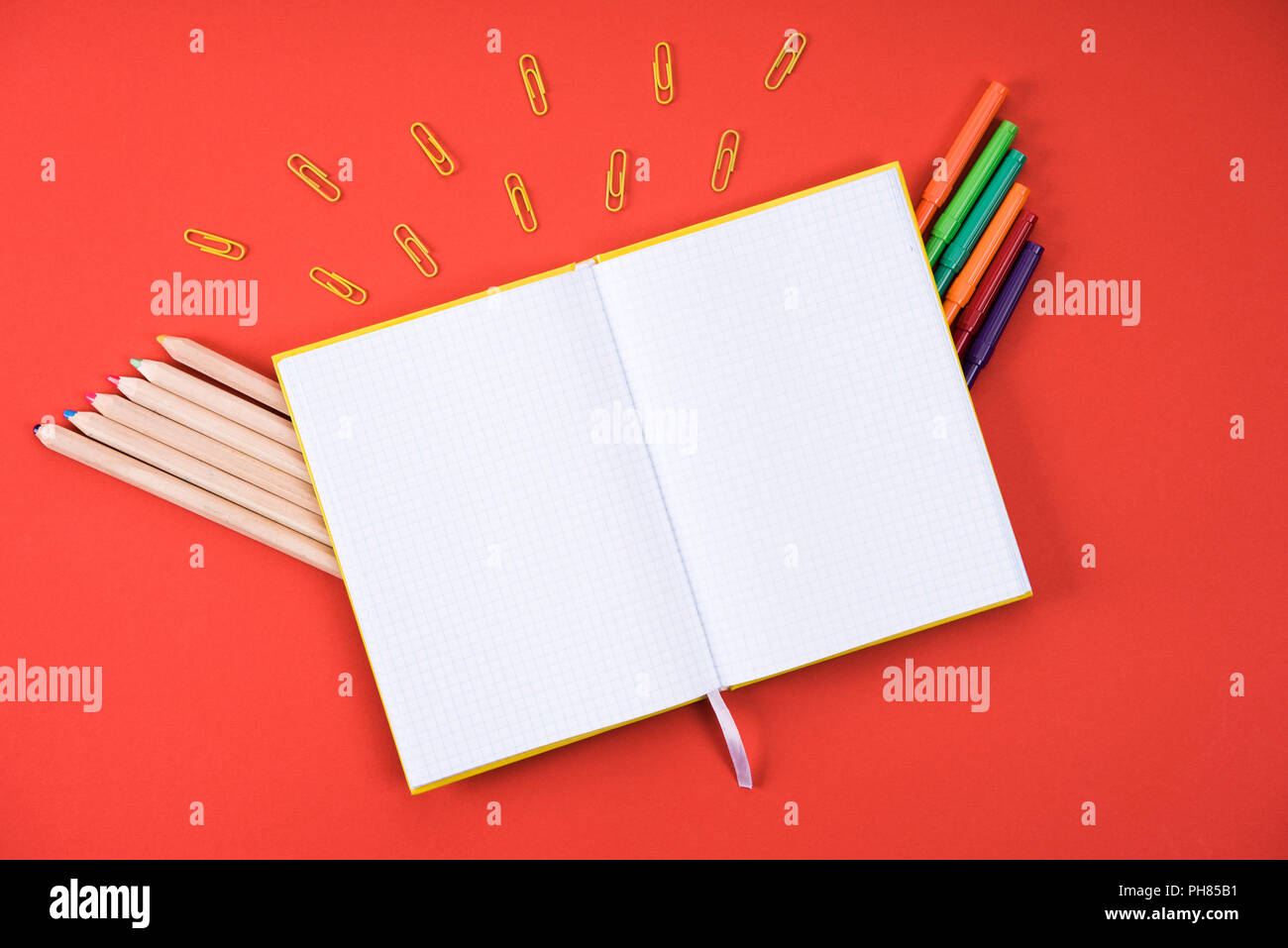 flat lay with opened blank notebook with paper clips, color pencils and ...