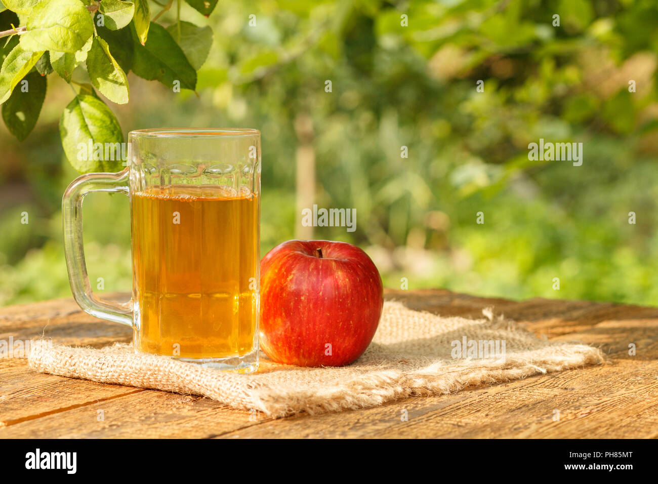 Apple cider in glass goblet and fresh red apple on wooden boards with ...