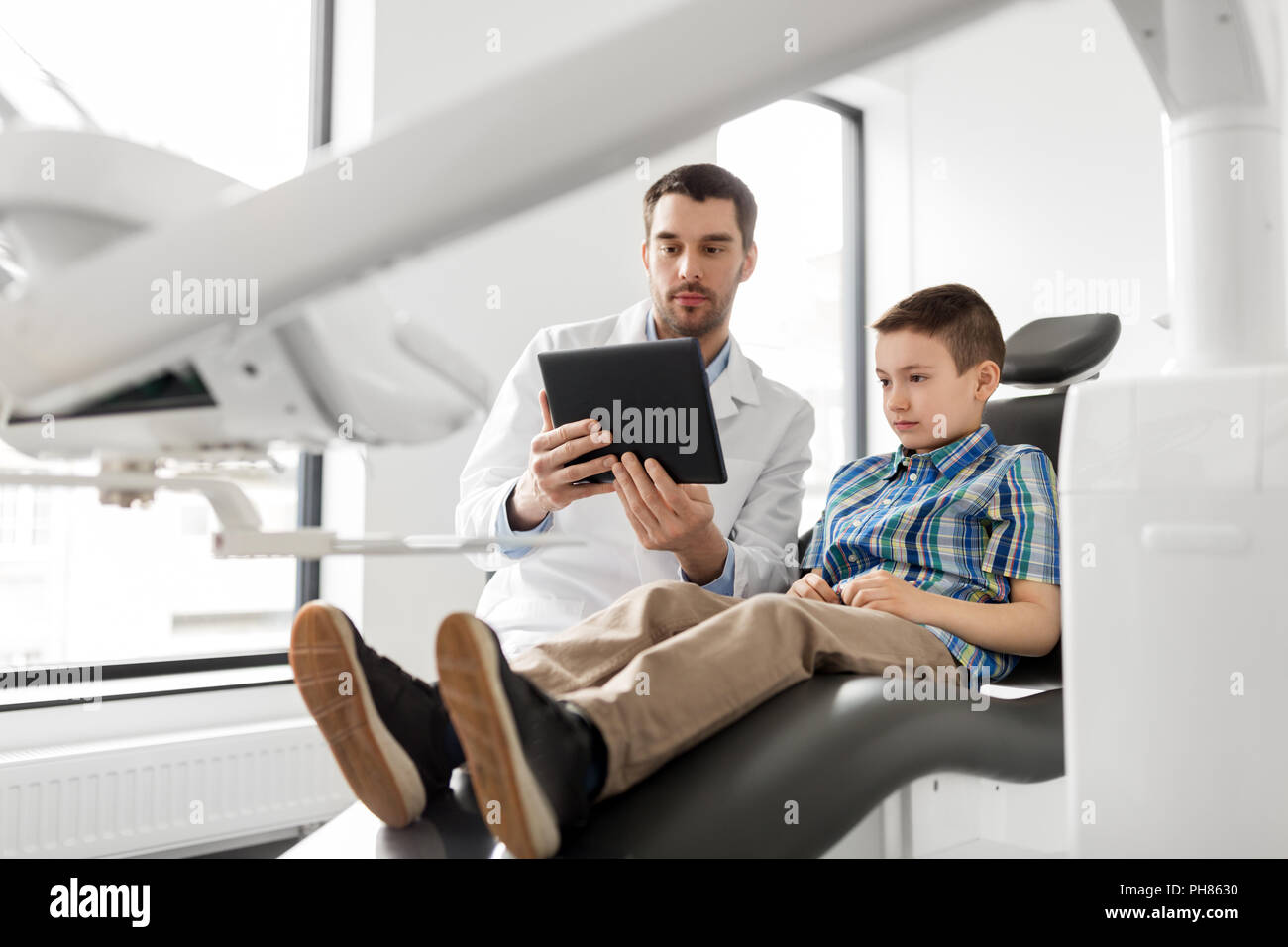 dentist showing tablet pc to kid patient at clinic Stock Photo - Alamy