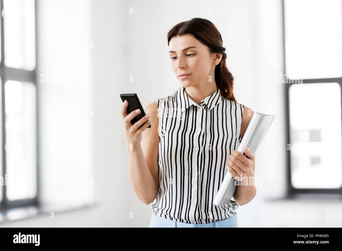businesswoman with smartphone and folder at office Stock Photo - Alamy