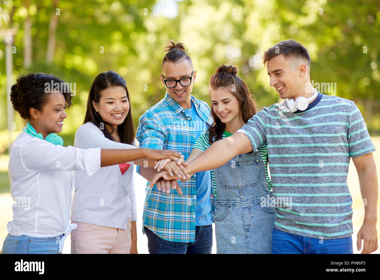 Happy friends stacking hands in hi-res stock photography and images - Alamy