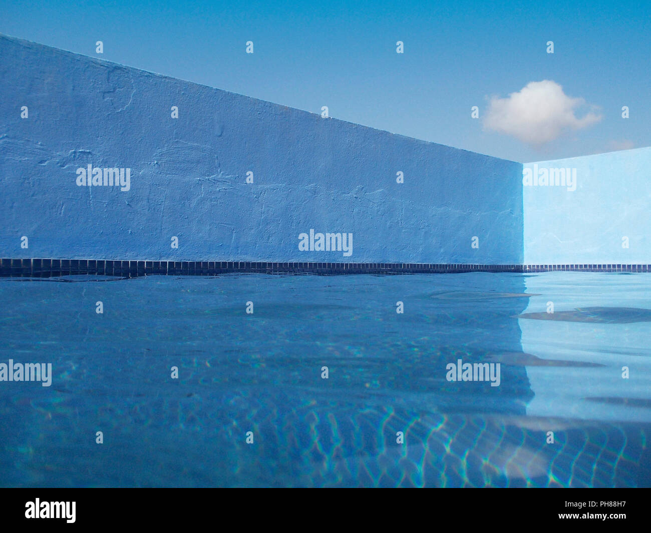 Outdoor swimming pool with blue sky and water reflections. Summertime ...