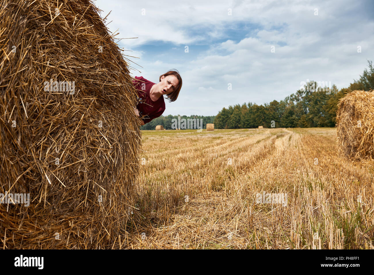 young girl having fun in the field, hiding behind a haystack Stock ...