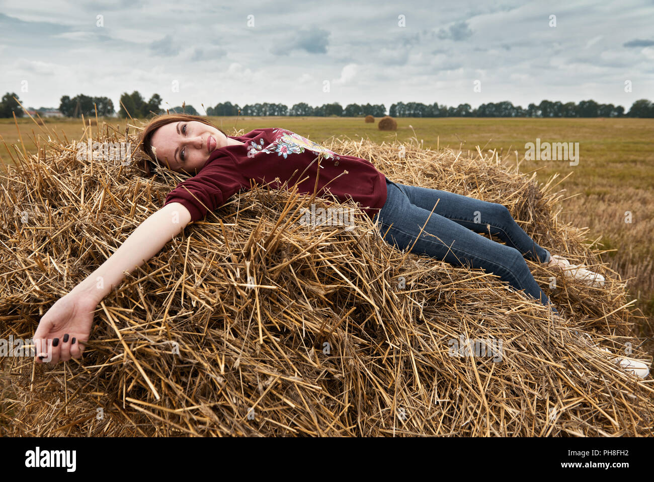 young girl having fun in the field, lying on a haystack Stock Photo - Alamy