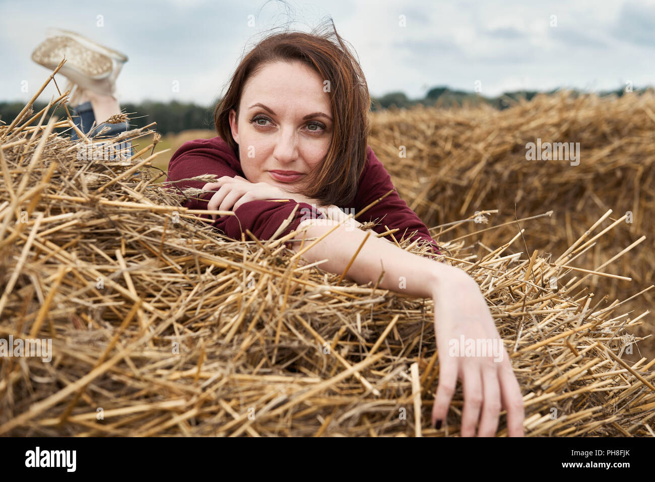 young girl having fun in the field, lying on a haystack Stock Photo - Alamy