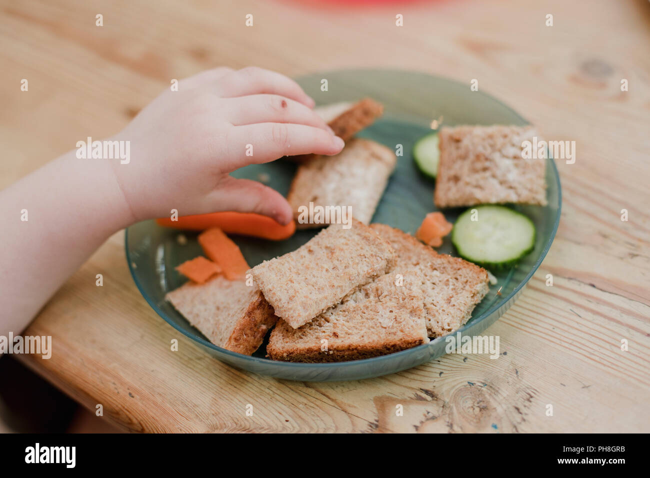 Point of view angle of a little girls hand reaching to pick some food ...