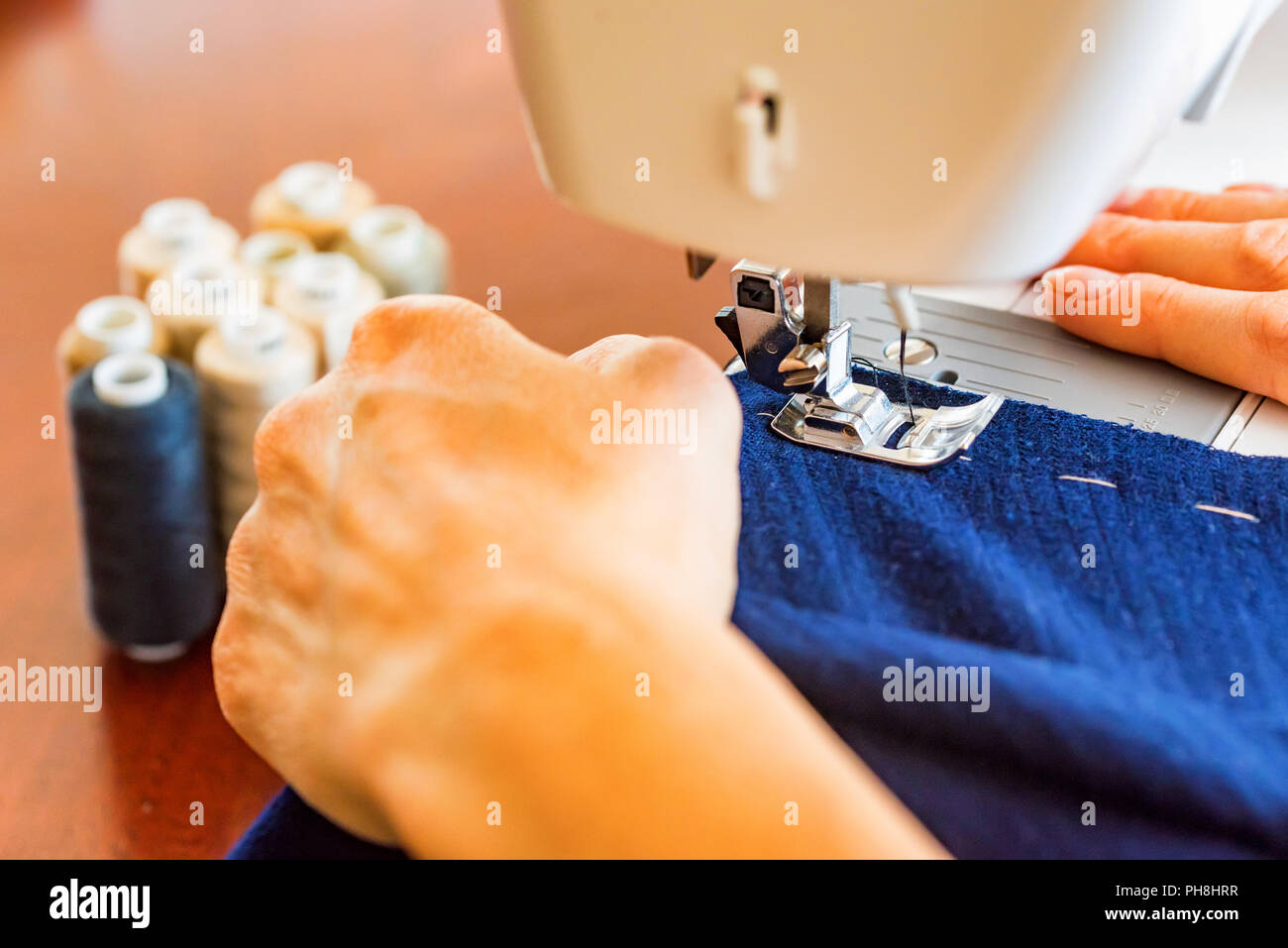 Dressmaker or seamstress works using sewing machine. Reels, scissors ...