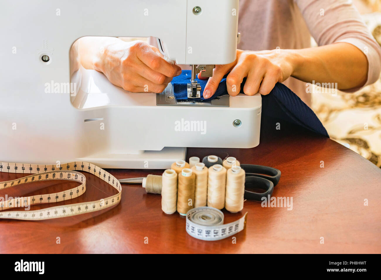 Dressmaker or seamstress works using sewing machine. Reels, scissors ...