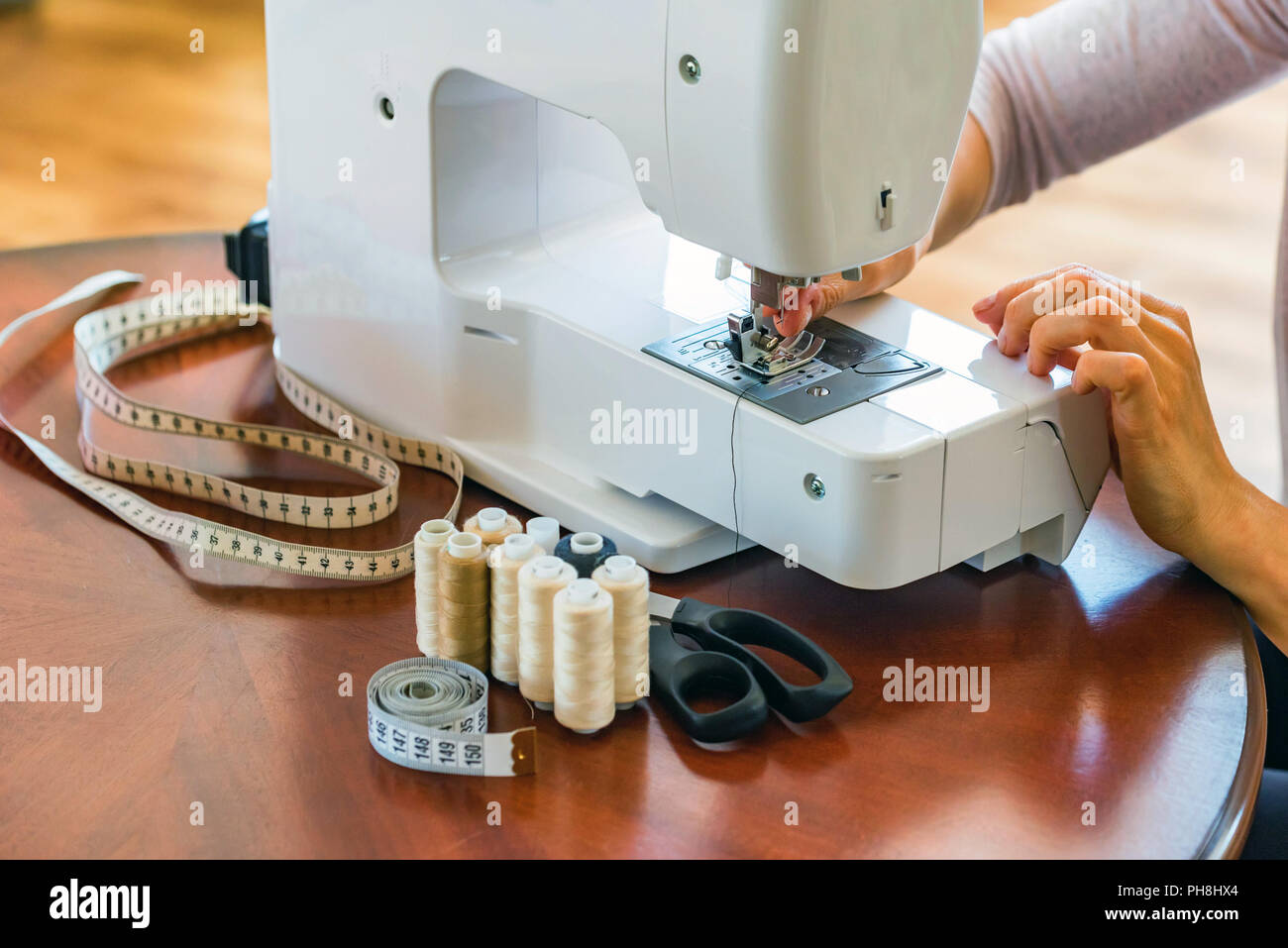 Dressmaker or seamstress works using sewing machine. Reels, scissors ...