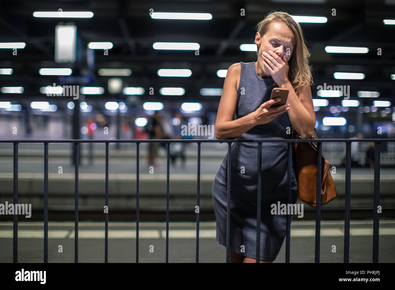 Pretty, young female commuter, looking exhausted, waiting for her daily ...