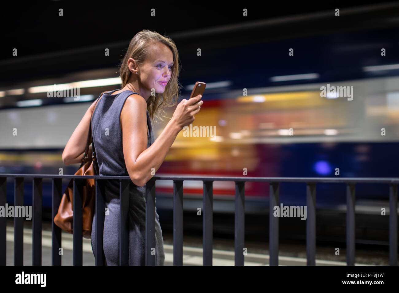 Pretty, young female commuter waiting for her daily train in a modern ...